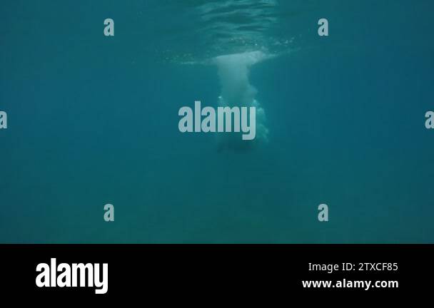 Active man jumping feet first in sea waves in summer in slow motion ...