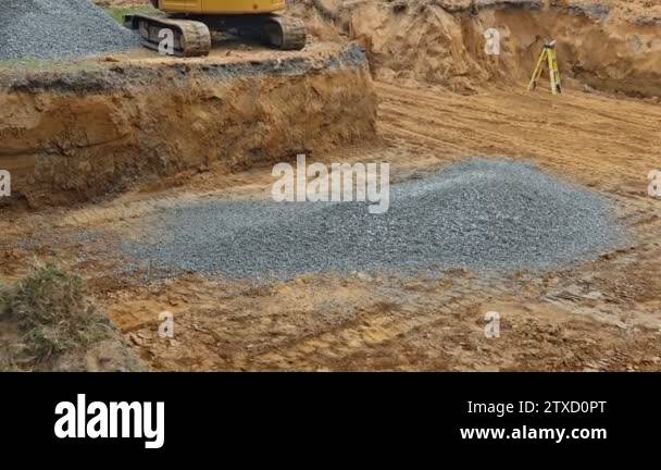 Excavator bucket backfilling trench for stone backfill of foundation ...