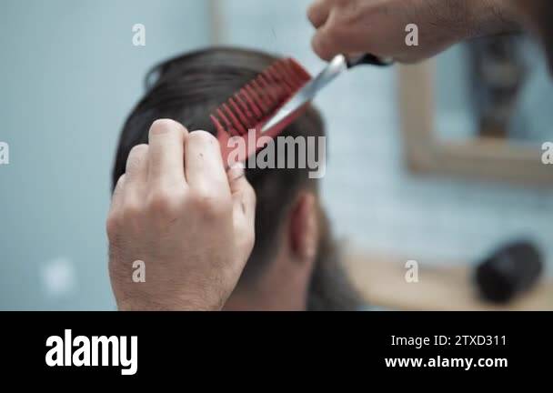 Close-up of barber cuts the hair by scissors at barbershop ...