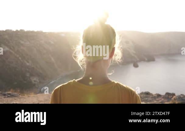 Slow motion back side view of female tourist walking to the edge of ...