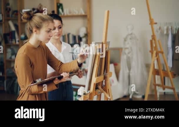 Cute teenage girl is learning painting from experienced teacher in art ...
