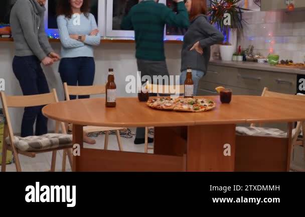 Guys and girls are dancing in the kitchen. Happy friends celebrating new years eve party at home ...