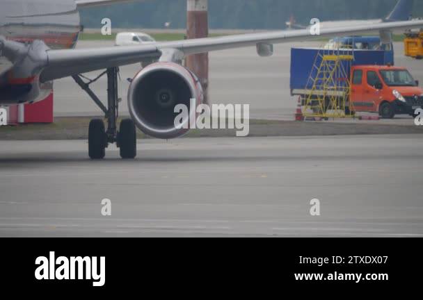 Working jet engine and landing gear of a jetliner moving on airport ...