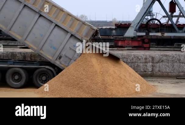 Grapple crane unloading and loading corn feed from truck in port ...
