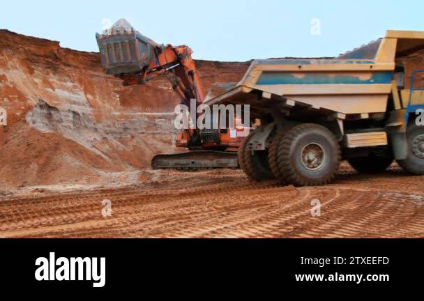 Excavator loading sand into tipper truck. Caterpillar excavator digging ...
