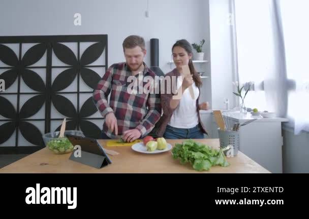 young funny woman with man dancing and having fun while cooking healthy ...