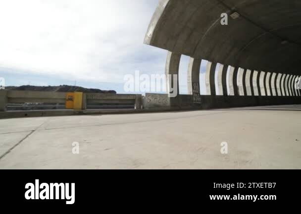 Hand held camera walking towards and getting in a brutalist concrete ...
