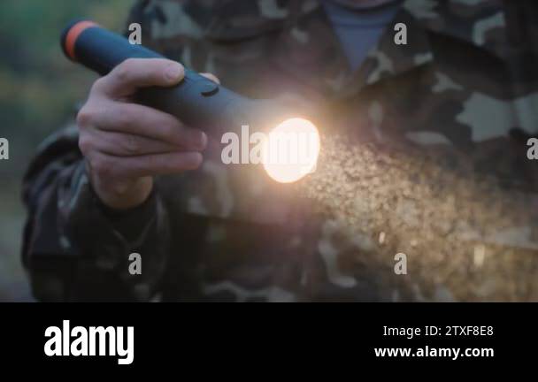 A hand with a flashlight illuminates the path in the forest, drops of ...