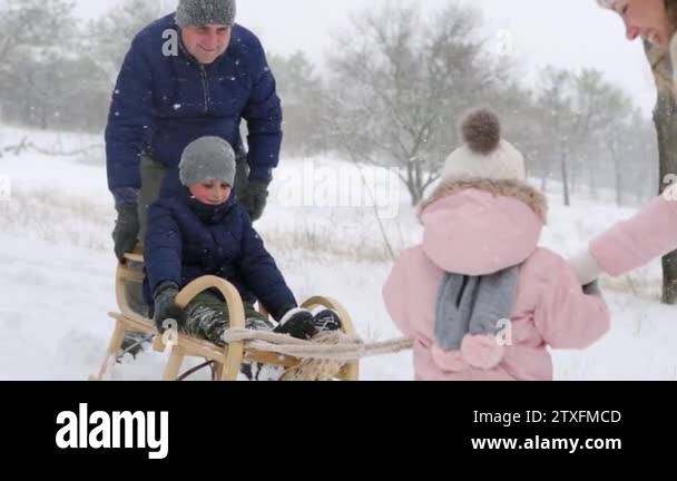 Happy family sledding on snowy winter day. Daughter helps father and ...