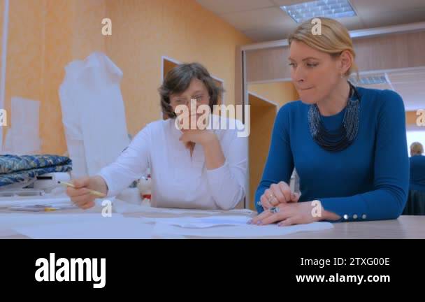 Two professional women tailors, designers discussing pattern of new ...