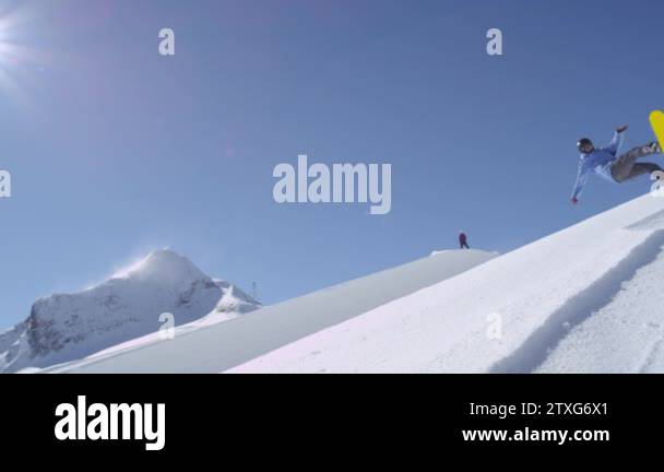 SLOW MOTION: Young pro snowboarder riding the half pipe in big mountain ...