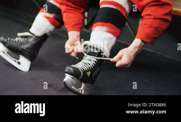 Young male ice hockey player tying skate in dressing room 4k Stock ...
