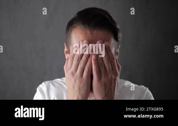 Portrait of Young man in despair crying covering his face with his hand ...