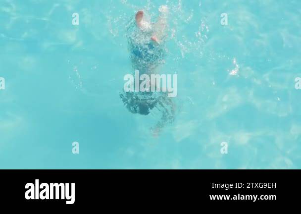 Cheery woman dives in a swimming pool and touches the bottom in slow ...