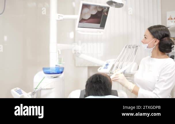 Dentist examines with macro camera oral cavity of the patient. Young African American male ...