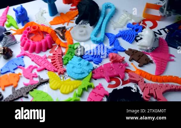 Many bright multi-colored objects printed on 3d printer lie on flat ...
