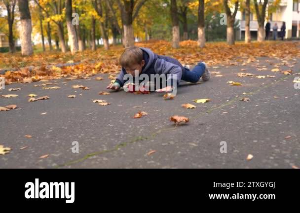 Young boy trying to ride skateboard by laying on his belly and pushing ...