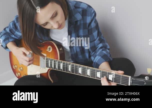 Young attractive female with electric guitar practicing songs before ...