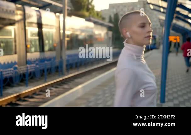 unusual dance of young bald caucasian girl on platform with train ...