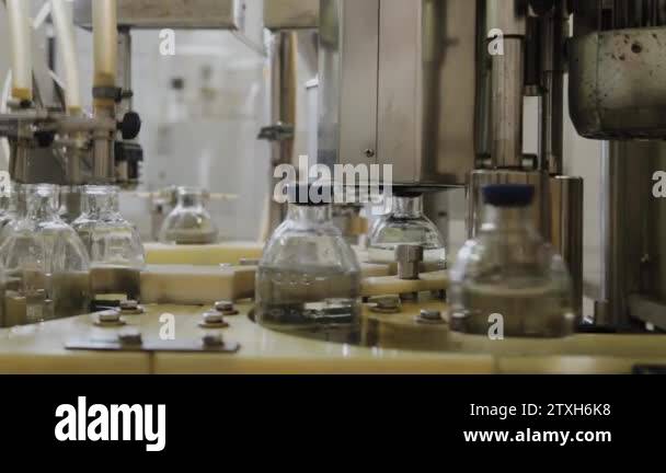 Pouring medicine on an assembly line into glass bottles for injection ...