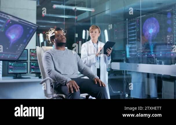 Man Wearing Brainwave Scanning Headset Sits in a Chair while Scientist ...