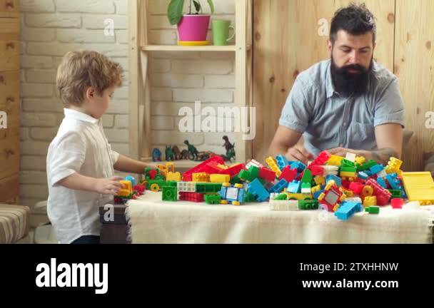 Father and son with happy faces create colorful constructions with toy ...