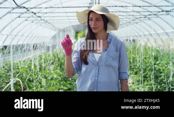 A beautiful girl in a straw hat and wearing rubber pink gloves, working ...