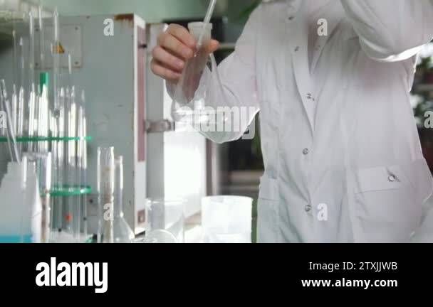 Chemical laboratory. Two young women making experiments. Pouring red ...