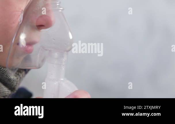 Sick boy inhaling through inhaler mask, nose and lips close-up side ...