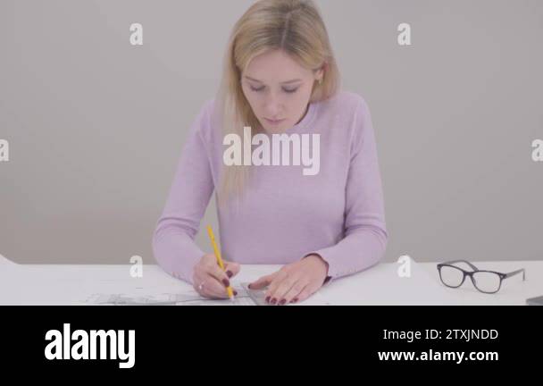 Portrait of concentrated Caucasian woman drawing blueprint, doing ...