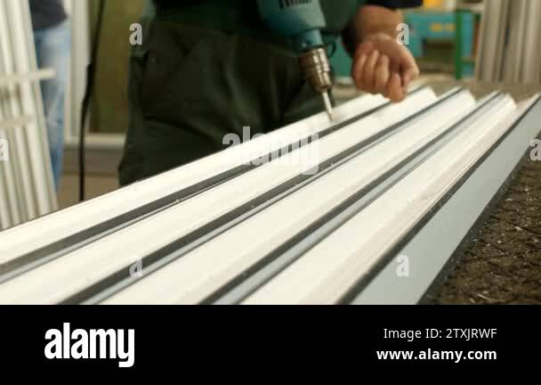 Manufacturing windows pvc, male worker twists screws in the profile pvc ...