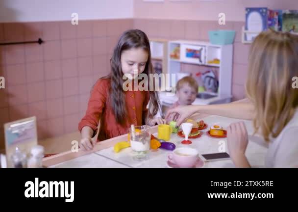 cute little girl is bringing artificial toy fruits for her mother ...