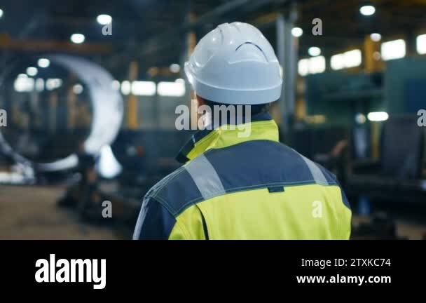 Industrial Engineer in Hard Hat and Safety Jacket Looks Around in Big ...