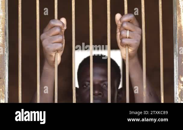 Jail, human rights,migration. Young african man behind prison's bars ...