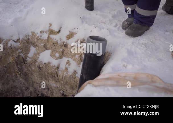 In the frame of a trench dug in frozen ground. Pipe made of steel and ...