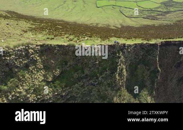 Two people on the edge of steep cliff look on huge caldera. Aerial of ...