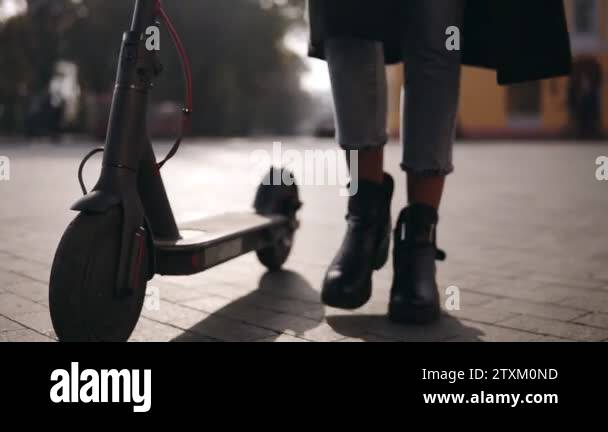 Close up of legs of a young woman scooter driver walking with her ...