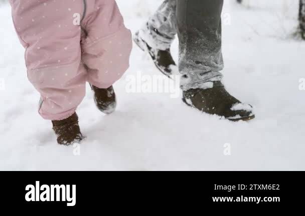 Baby feet in warm jumpsuit doing first steps. Child learns to walk ...