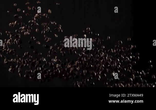 Roasted coffee beans fly after being exploded on black background ...