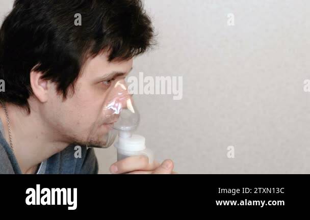 Use nebulizer and inhaler for the treatment. Young man inhaling through ...