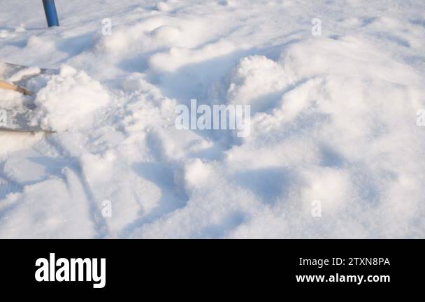 Shovel digs snow. Big mountain of snow. White cold snowdrift in the sun ...