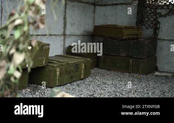 Wooden boxes with ammunition and weapons are hidden behind a camouflage ...