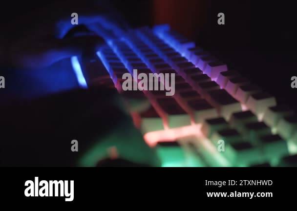 Male gamer typing and pressing keys on white gaming RGB keyboard in ...