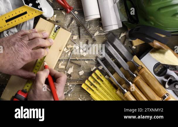 Top view. Carpenter measures a wooden board and with the pencil and the carpenter's square ...