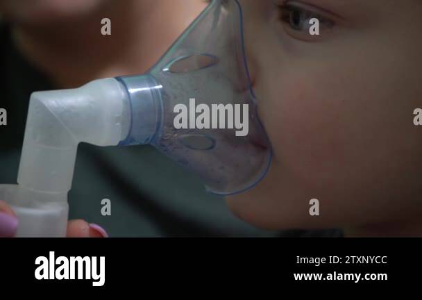 A child of three years old breathing in an oxygen mask. Inhalation of ...