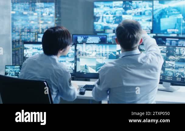 In the Security Control Room Two Officers Monitoring Multiple Screens ...