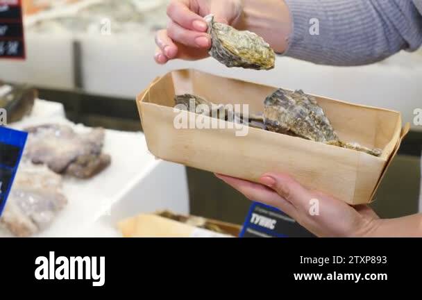Variety of fresh oysters in wooden boxes on shellfish counter at fish ...