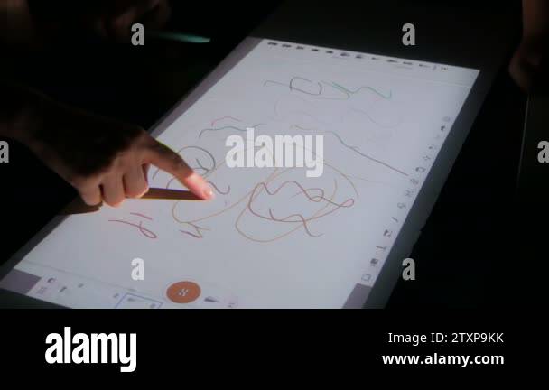 Woman using interactive touchscreen projector display for drawing at ...