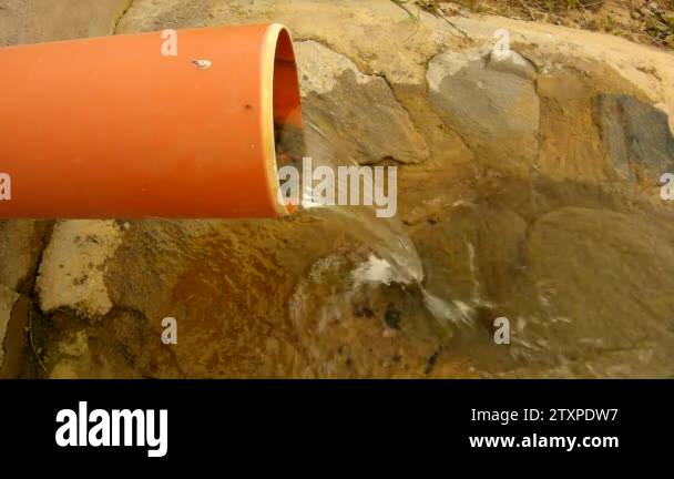 Splashing water from the drain plastic pipe is running down to boulder ...