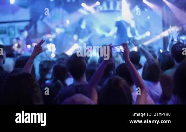 girl capturing a concert with a smartphone, large group of happy people ...